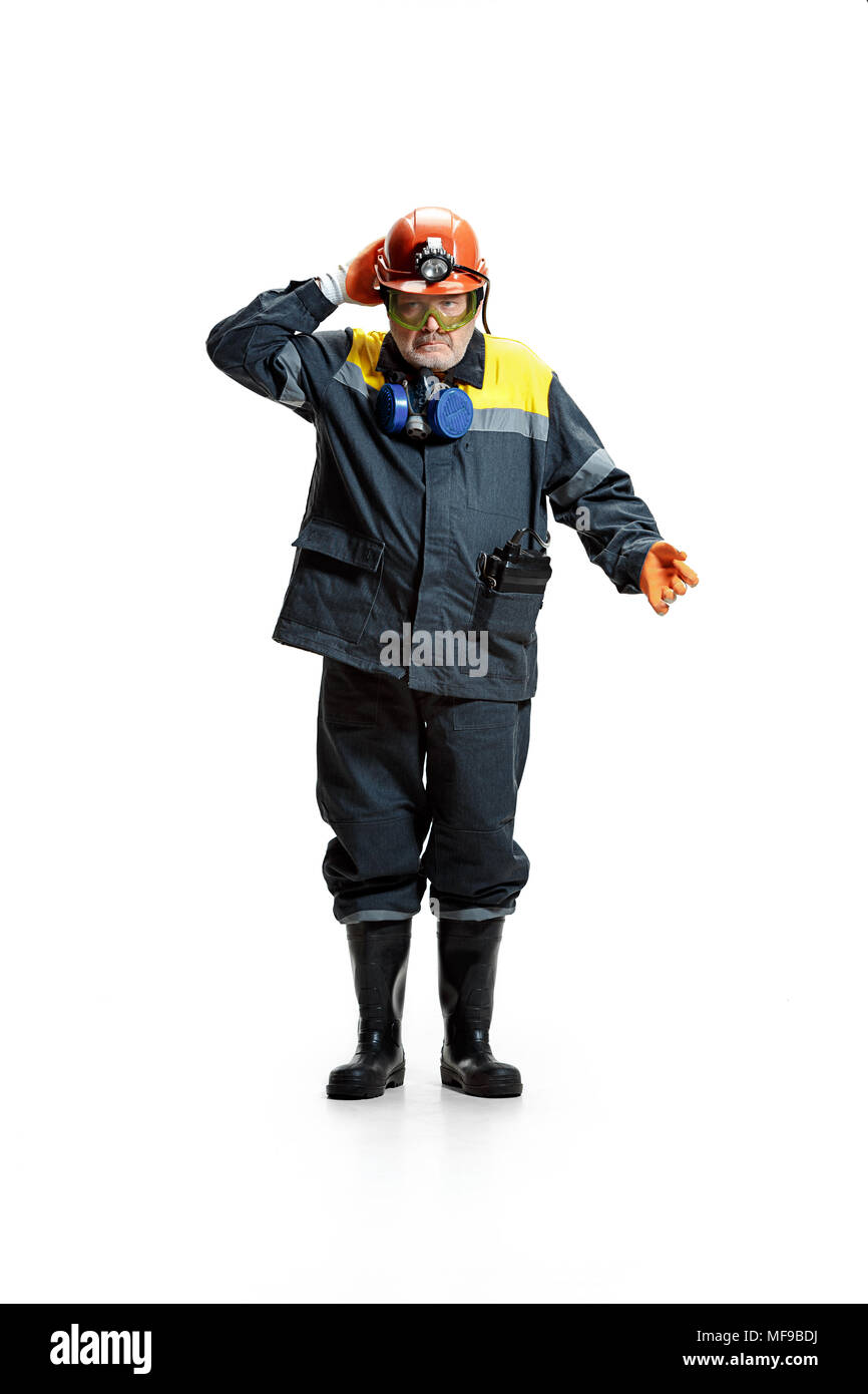 The studio shot of senior bearded male miner standing at the camera on ...