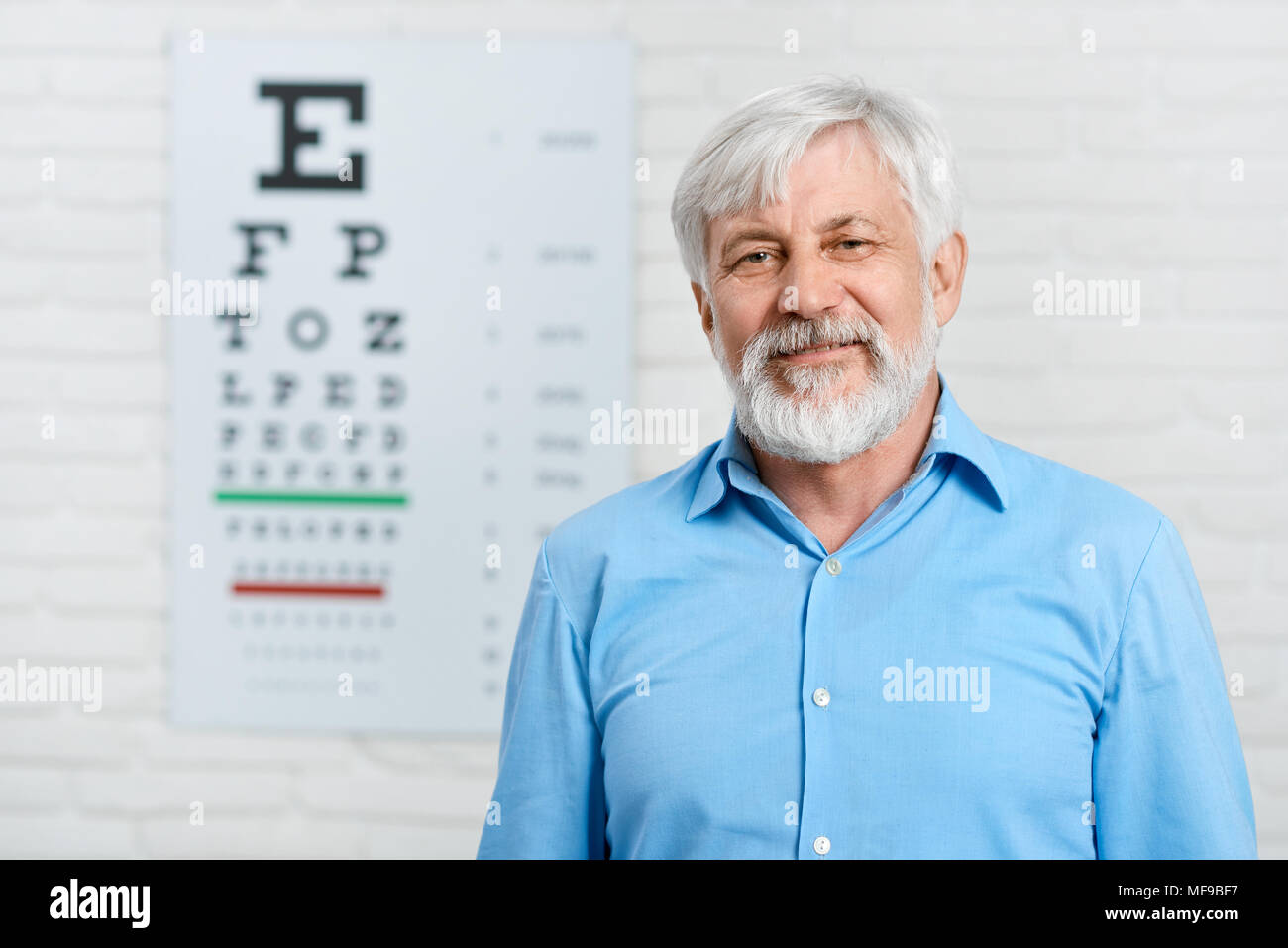 Old patient staying in front of visual inspection table hanging on ...