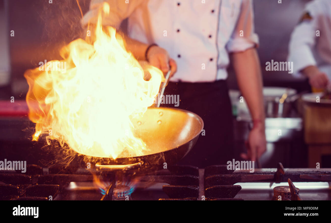 Chef cooking and doing flambe on food in restaurant kitchen Stock Photo ...