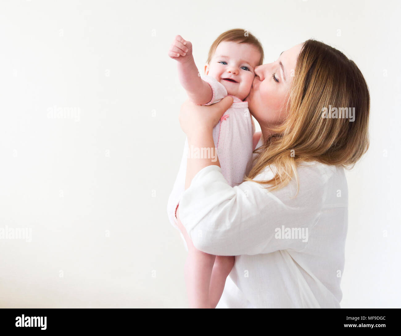 Young woman in the morning embrace and kissing with small girl. Happy ...