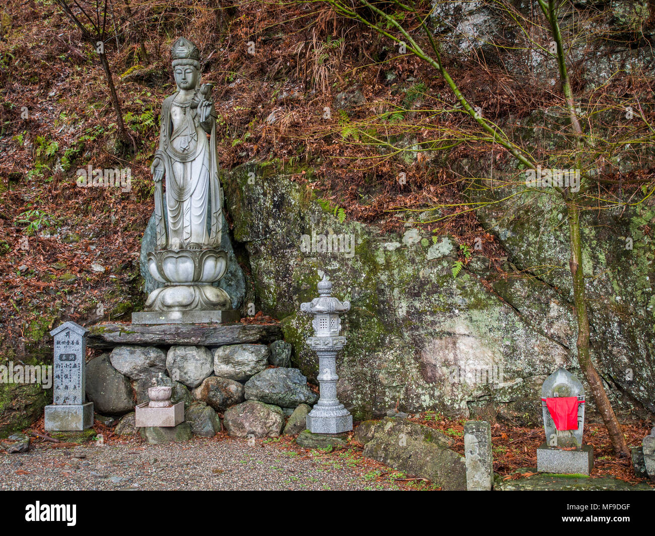 Statue of Kannon Bosatsu with red bib Jizo and ishidoro stone lantern ...