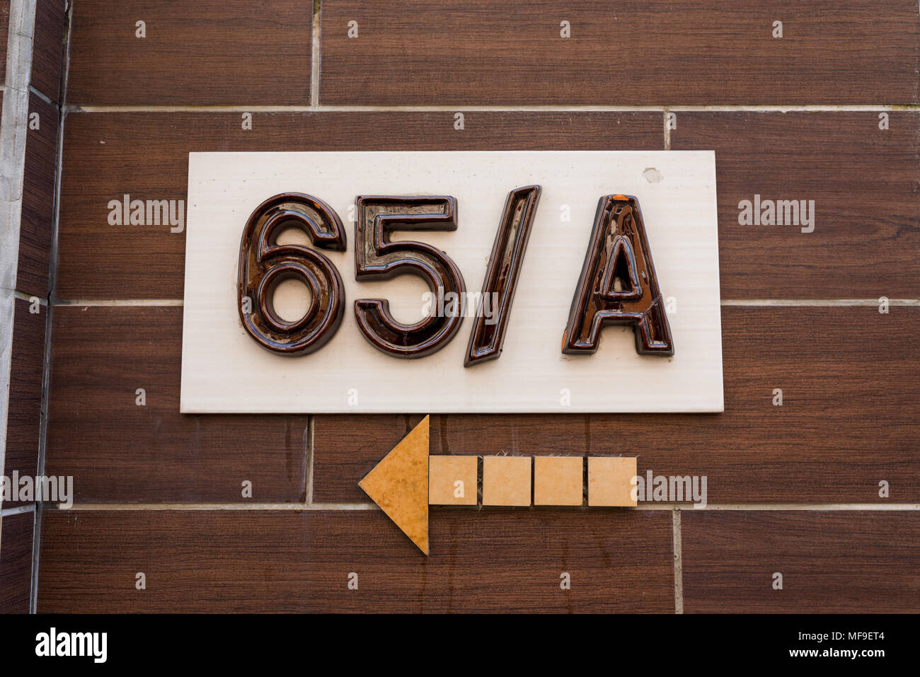 ceramic house number on the wall and arrow direction Stock Photo - Alamy