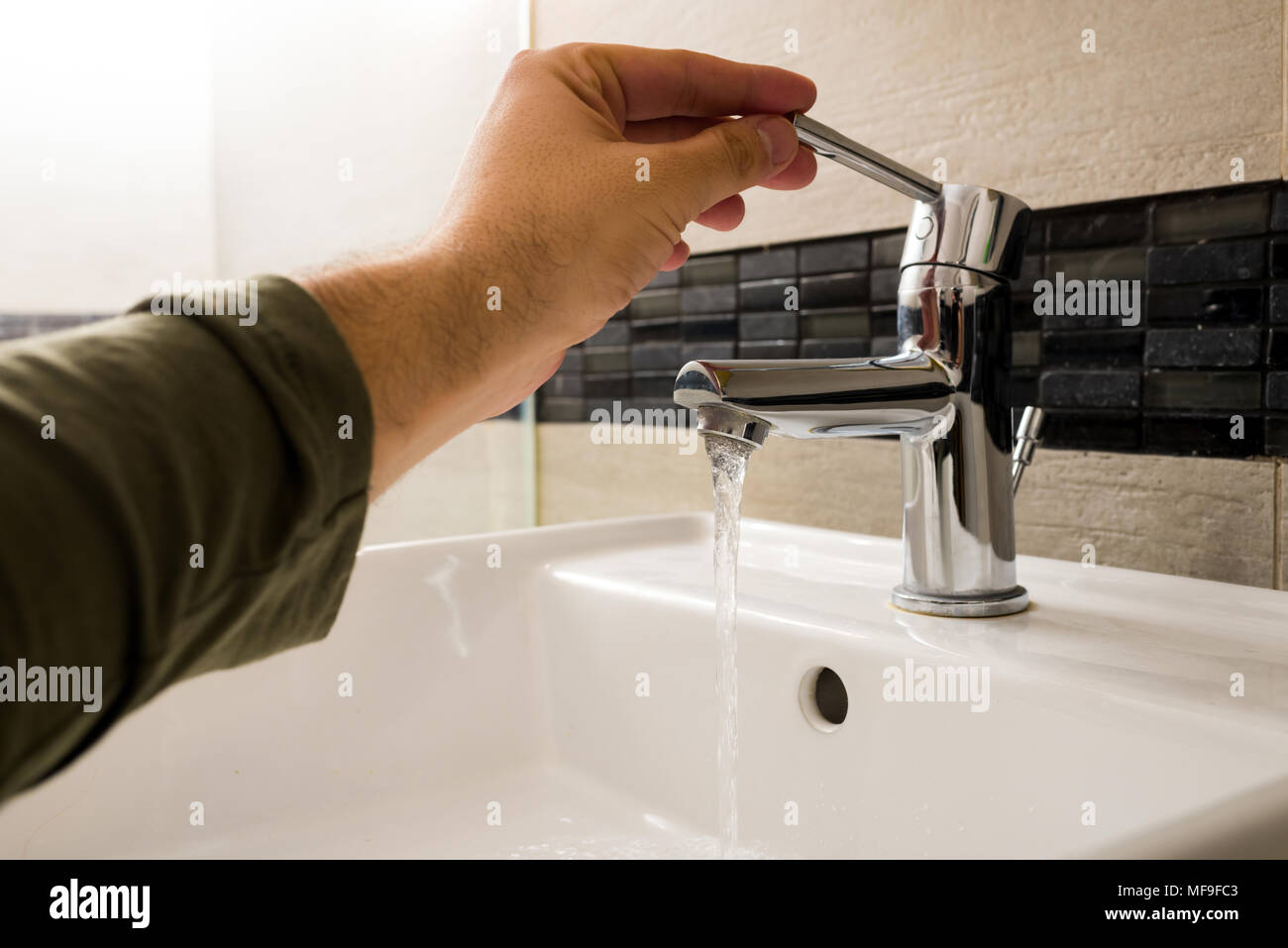 The man's hand opens the tap with Stock Photo - Alamy