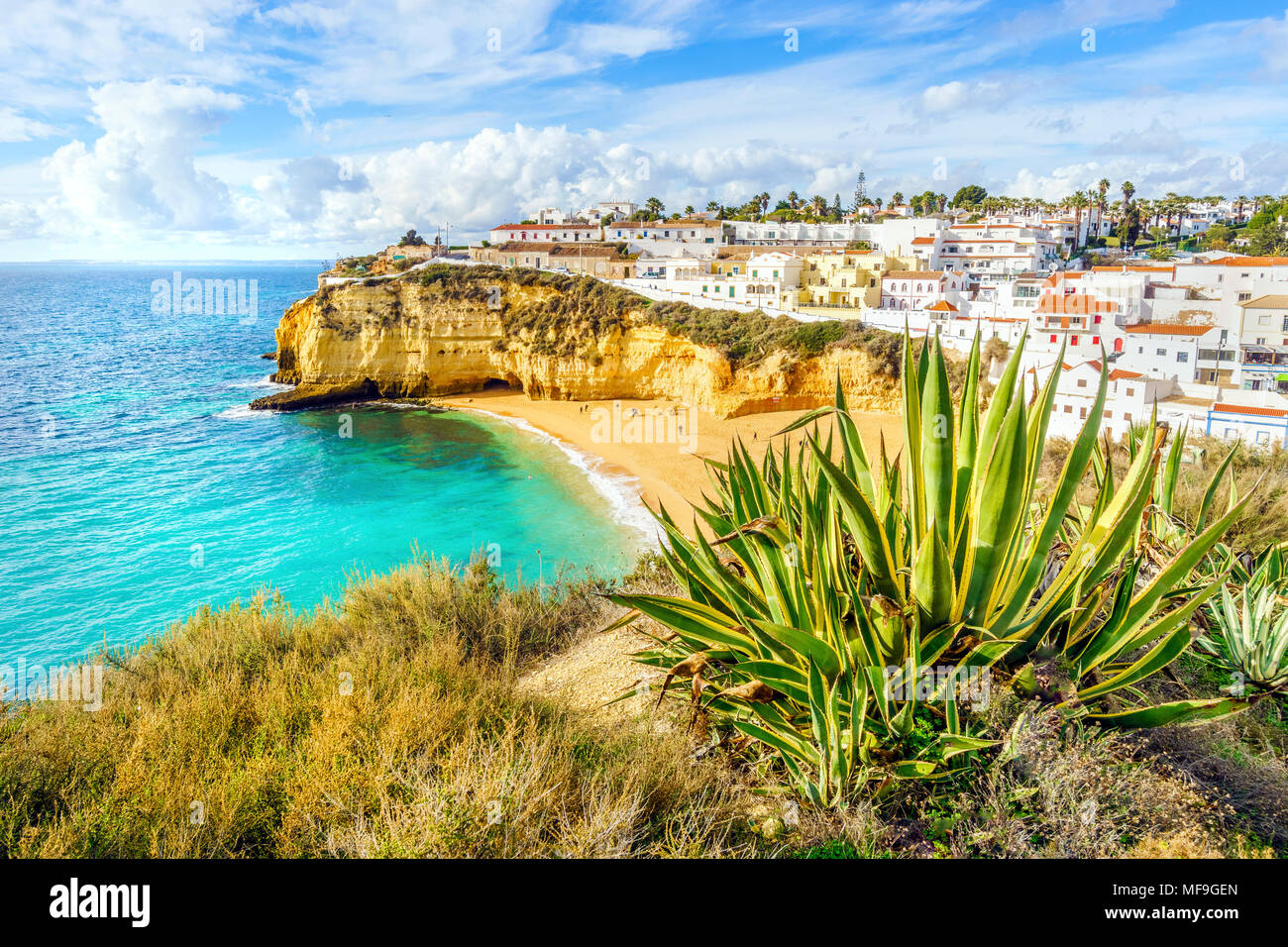 Sandy beach between cliffs in front of charming white architecture of ...
