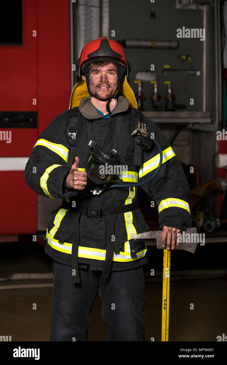 handsome young fireman holding fire hose in uniform Stock Photo - Alamy