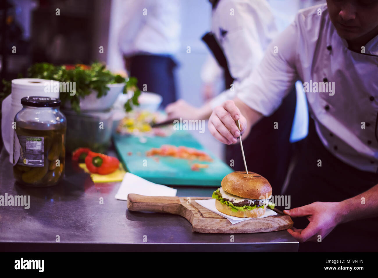 master chef putting toothpick on a burger in restaurant kitchen Stock ...