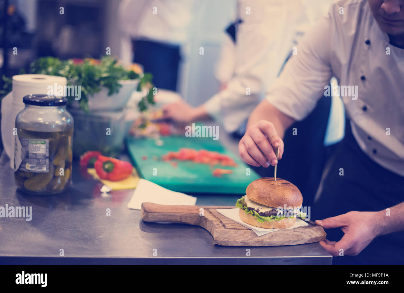 master chef putting toothpick on a burger in restaurant kitchen Stock ...