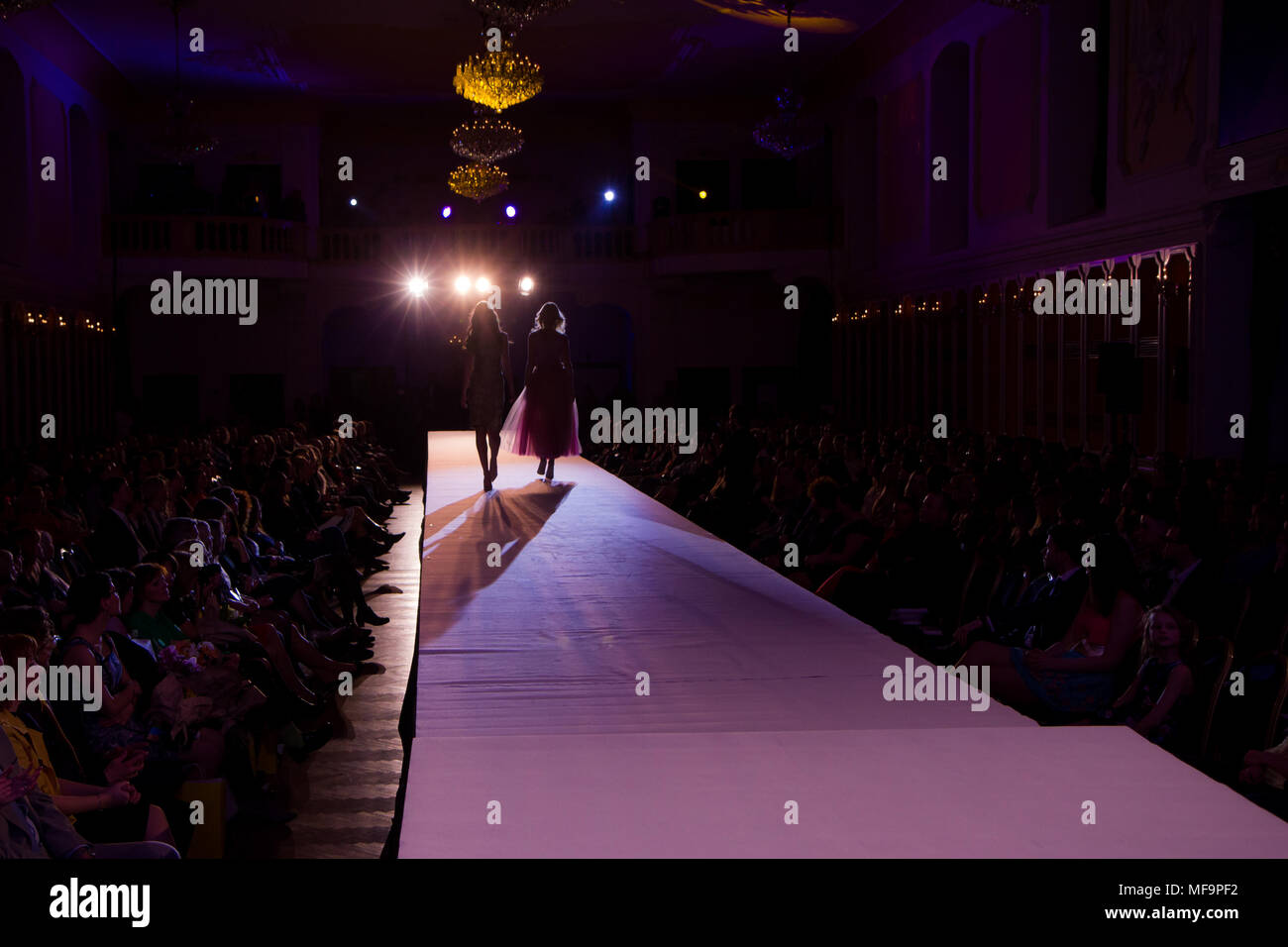A picture from a fashion show. The models are walking on a catwalk and ...