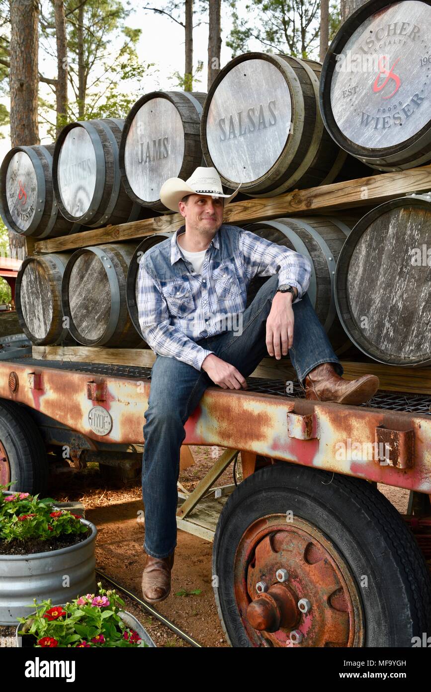 Western cowboy sitting on flatbed trailer with whisky casks or barrels ...