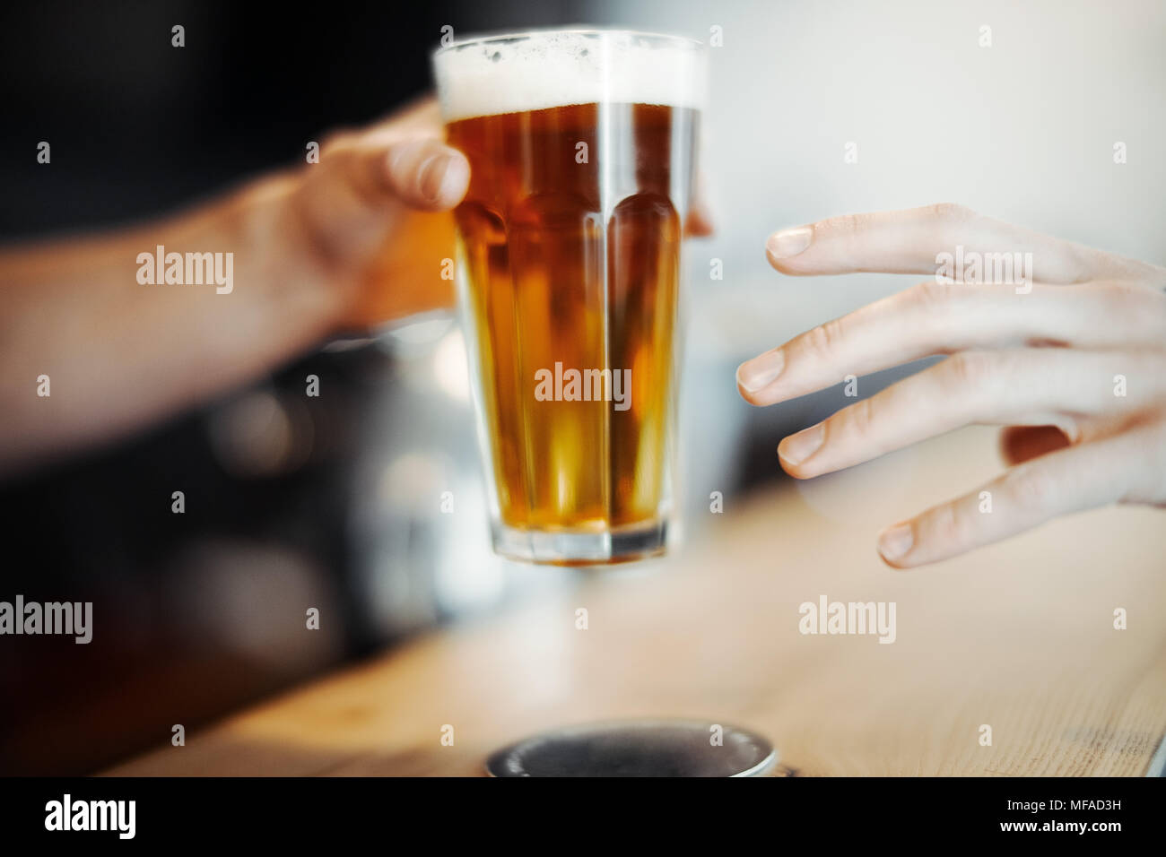 Bartender man gives beer glass to a customer Stock Photo - Alamy