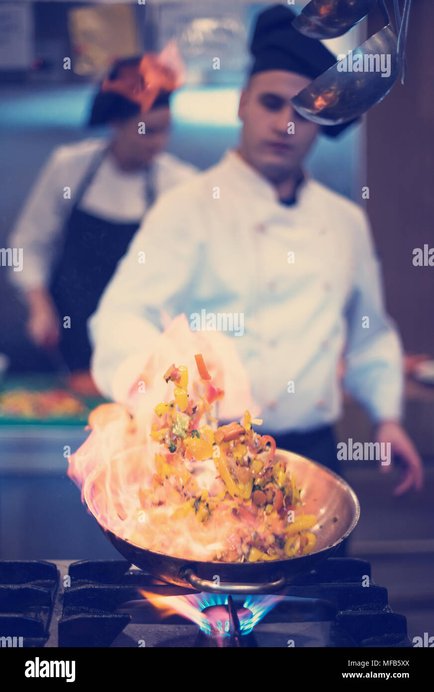 Chef cooking and doing flambe on food in restaurant kitchen Stock Photo ...