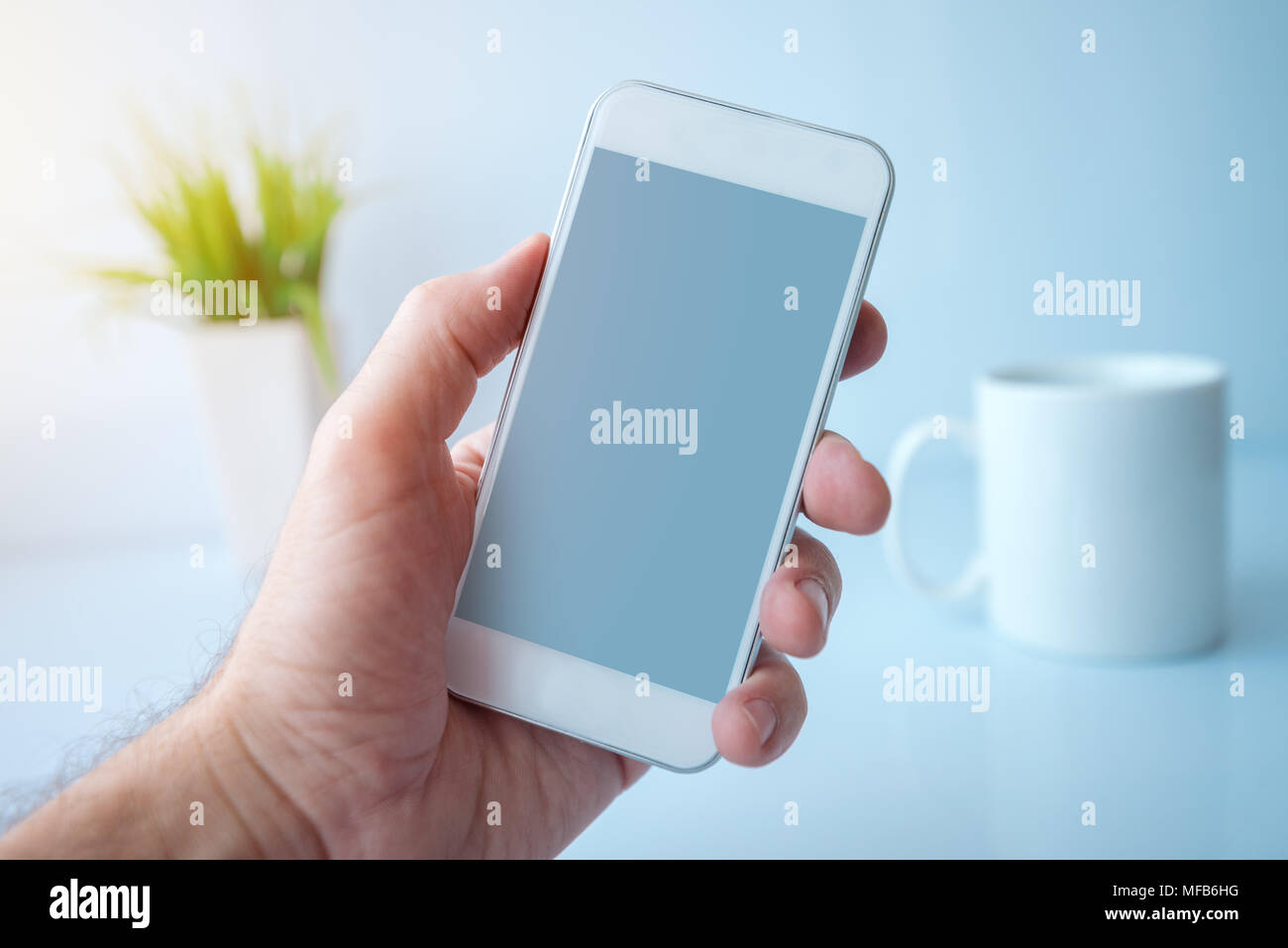 Using smartphone during coffee break in the morning, male hand holding ...