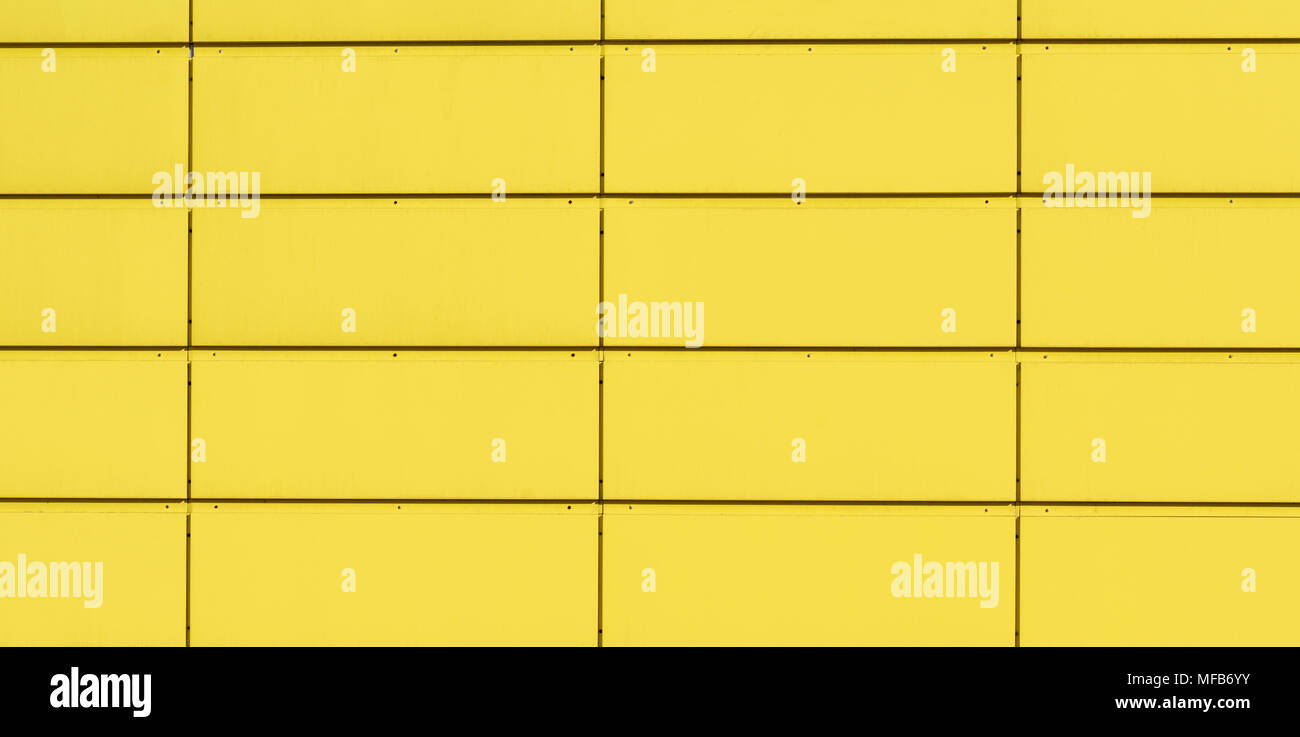 fragment of a yellow iron wall made of rectangular blocks with rivets ...