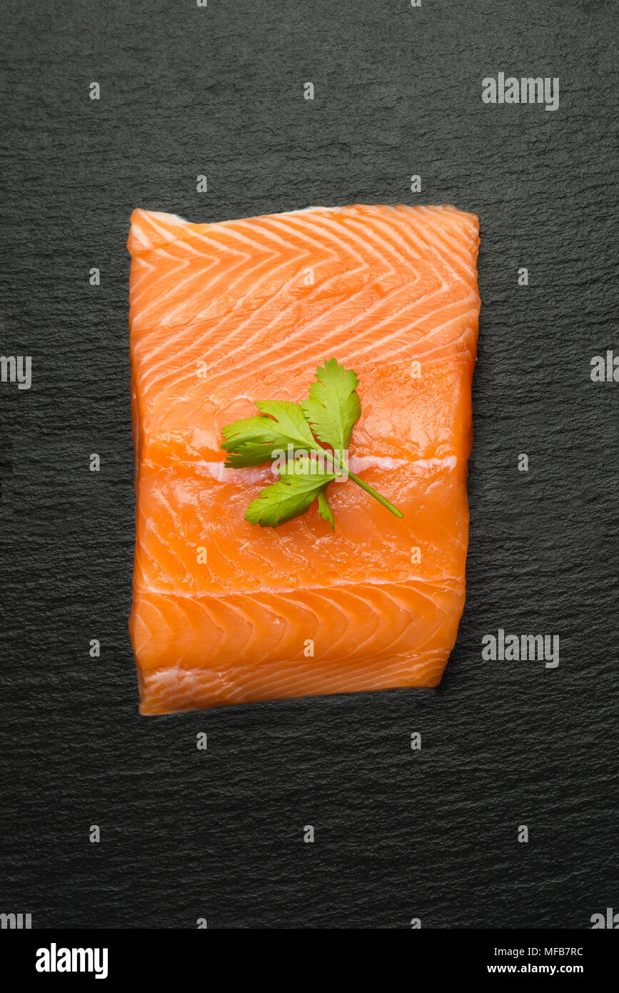 Top view of salmon fillet with coriander in black background Stock ...