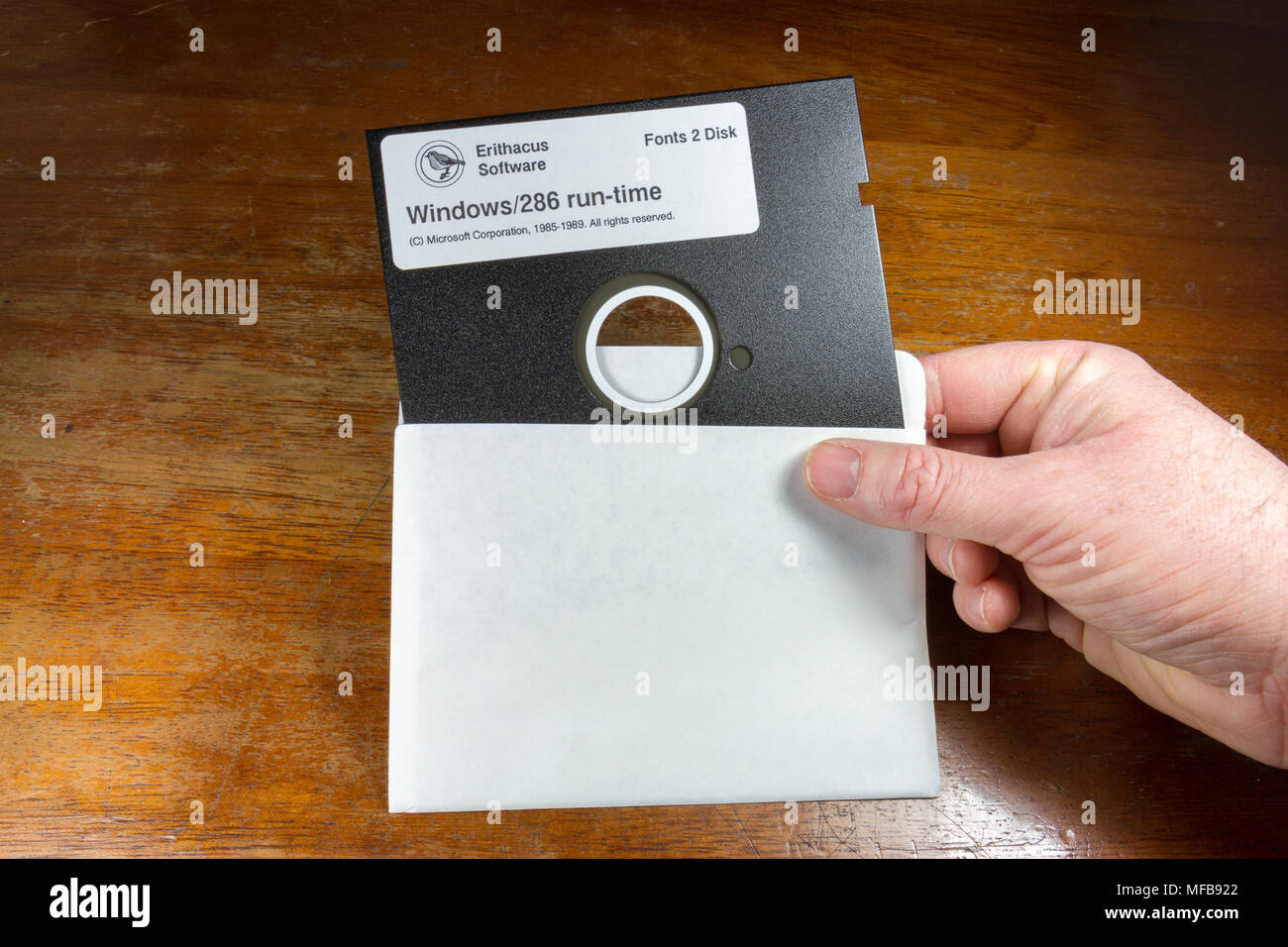 A 5¼-inch floppy disk being held in the right hand of a man with a ...