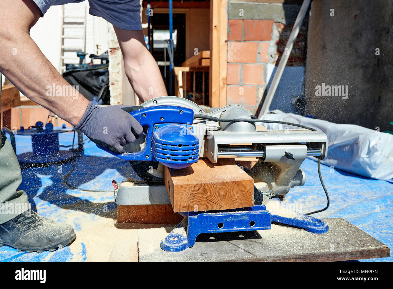 Blue collar carpenter using electric saw for wood cutting on site Stock ...