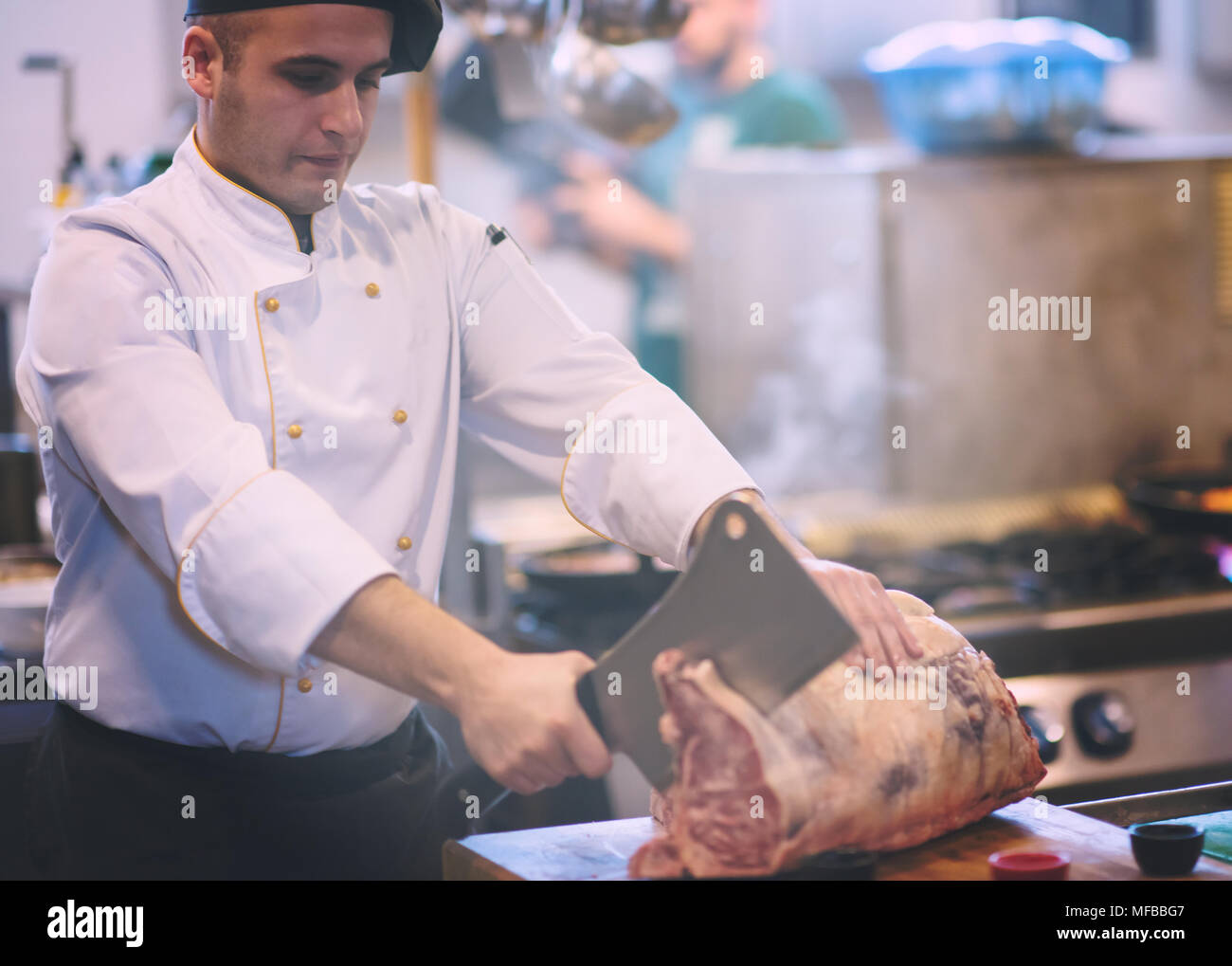 chef using ax while cutting big piece of beef on wooden board in ...