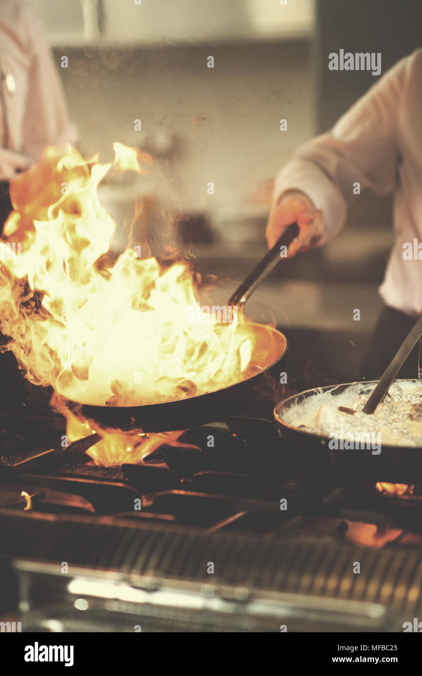 Chef cooking and doing flambe on food in restaurant kitchen Stock Photo ...