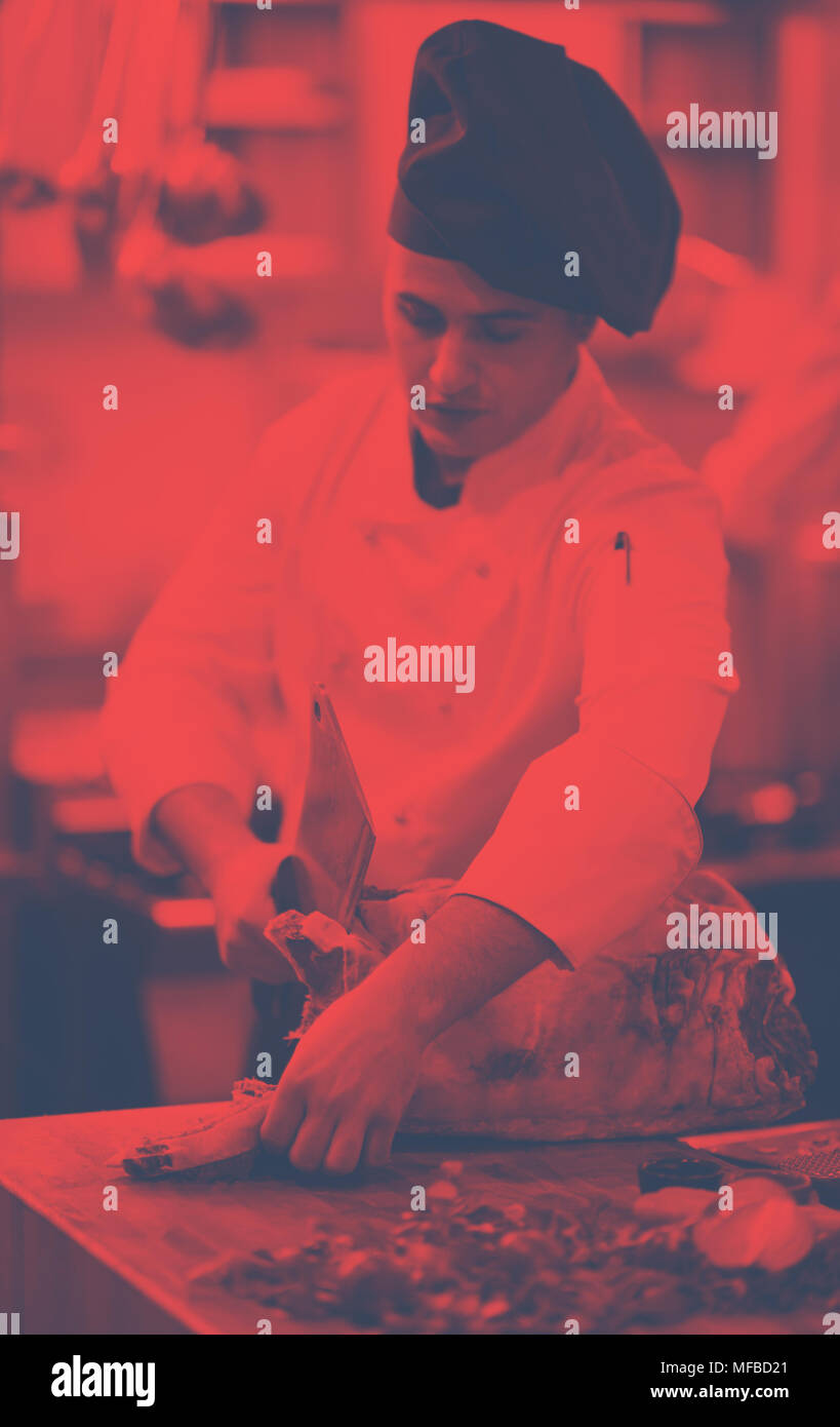 chef using ax while cutting big piece of beef on wooden board in ...