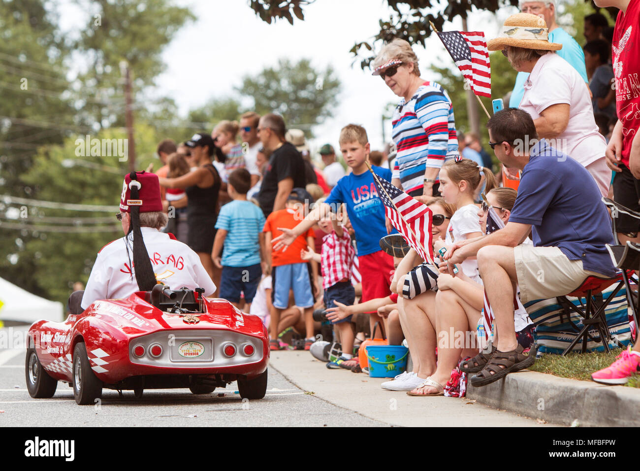 Families sit on curb with American flags and interact with people on ...