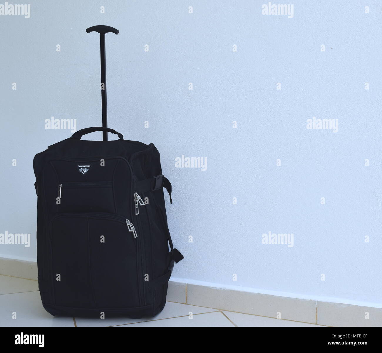 Black suitcase with a beautiful silk scarf on white textured background ...