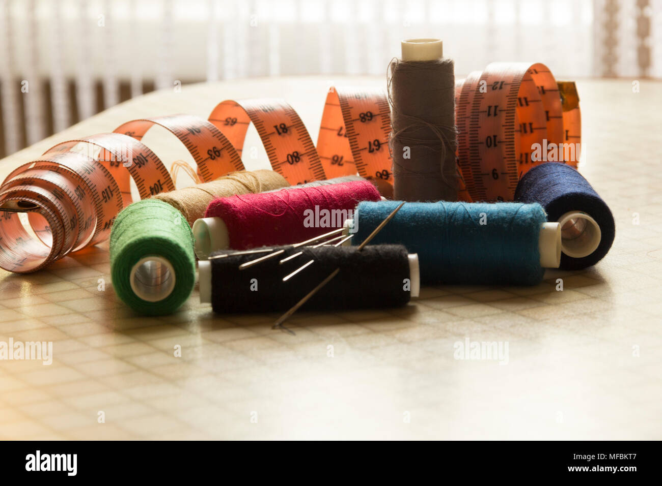 A set of multi-colored threads on bobbins lies on a checkered table ...