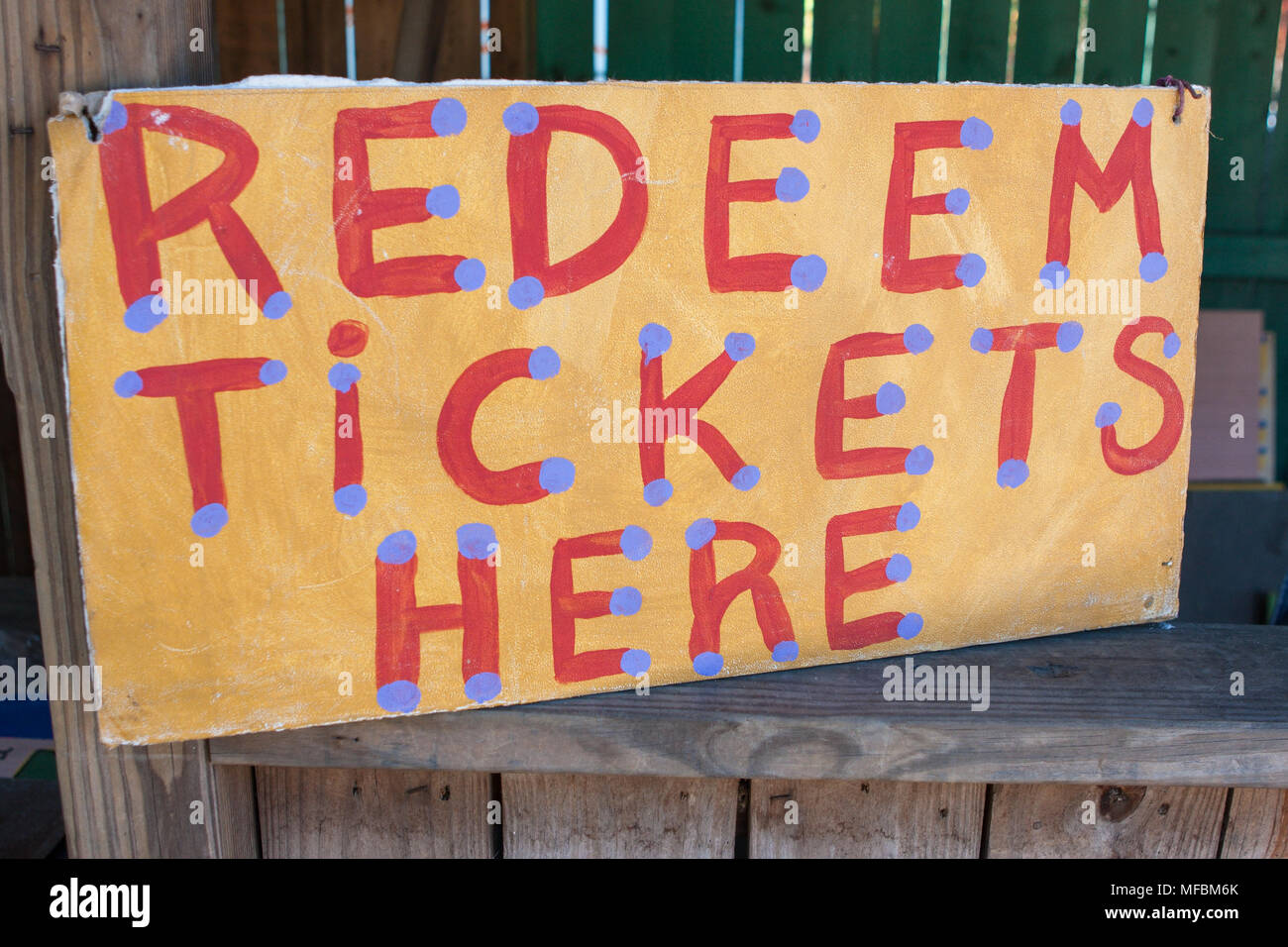 Handmade sign reading "Redeem Tickets Here" sits at booth of carnival ...