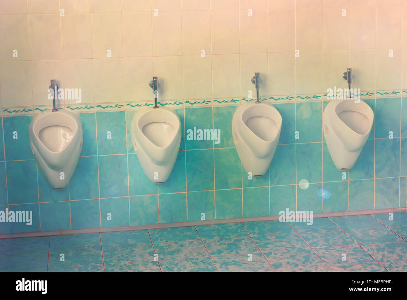Urinals in the toilet, ceramic tiles background Stock Photo - Alamy