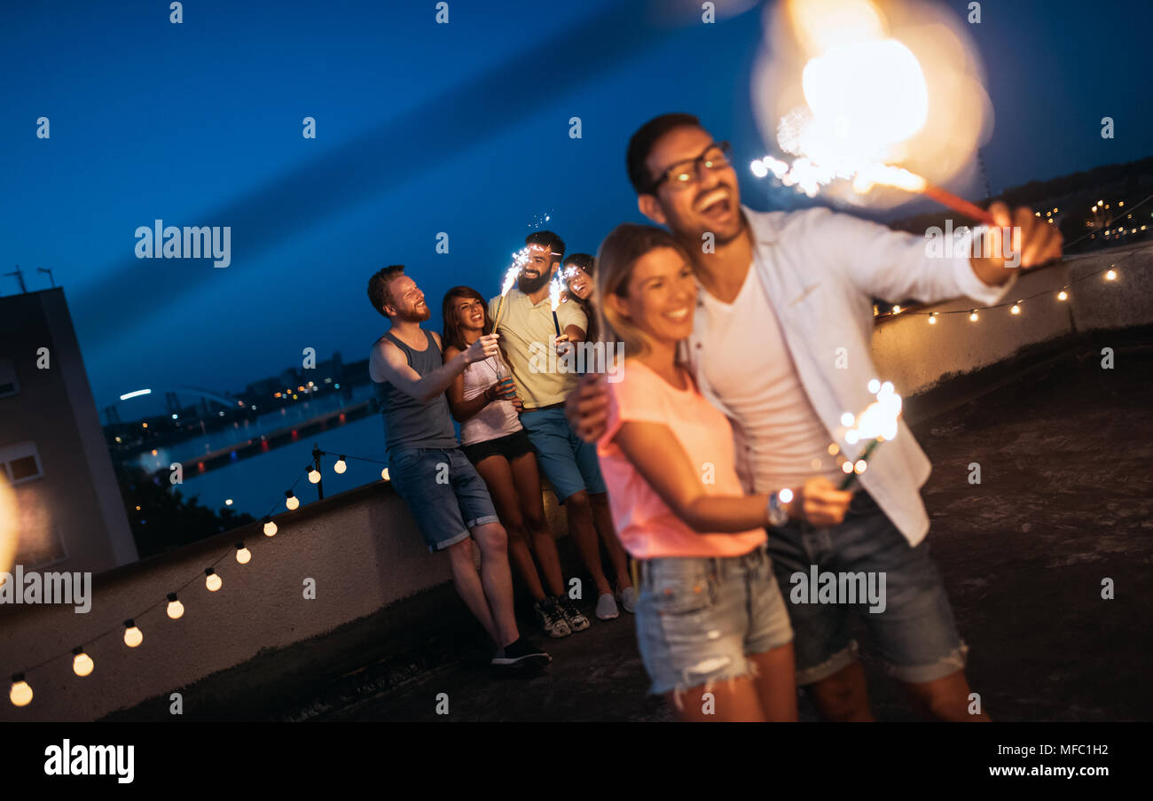Friends enjoying a rooftop party and dancing with sparklers Stock Photo ...