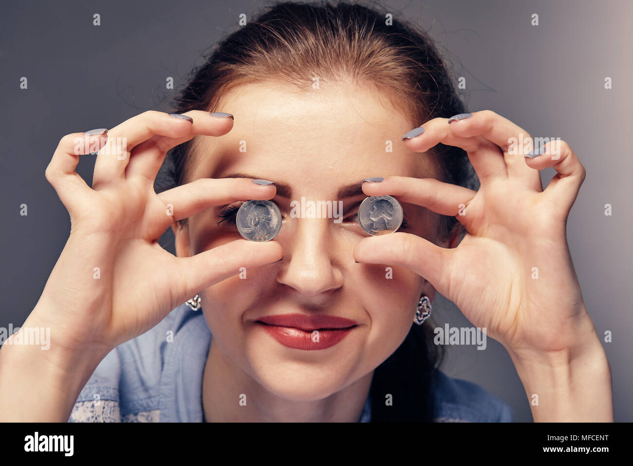 smiling girl with red lipstick holds golden coins in her hands, closes ...