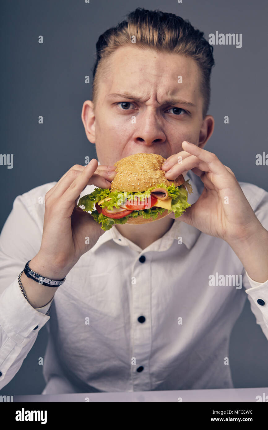 Young man eating a fresh burger Stock Photo - Alamy