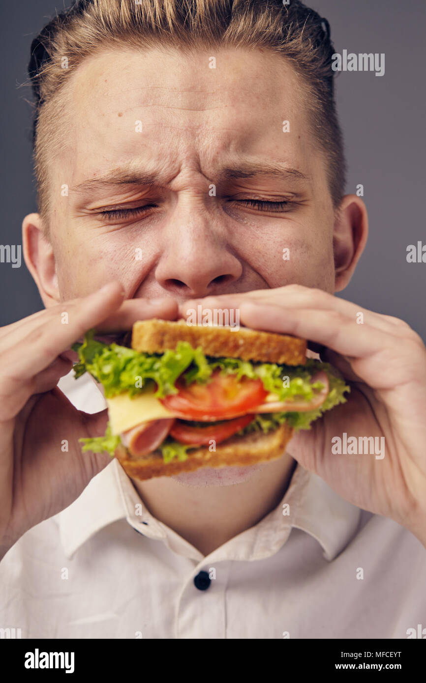 Young man eating a fresh burger Stock Photo - Alamy