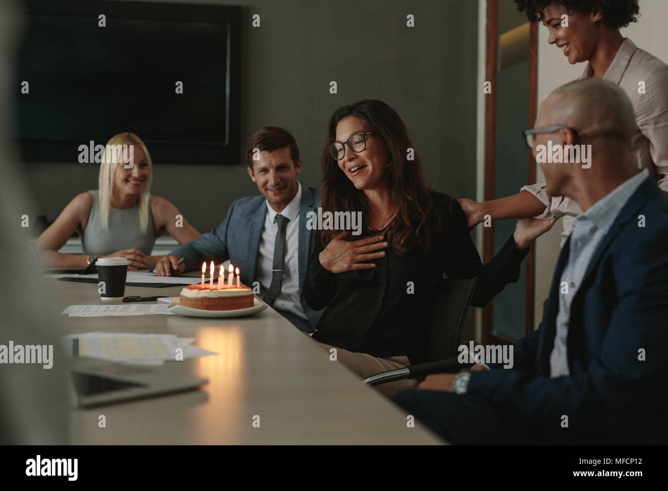 Office workers celebrating female colleague's birthday during a meeting ...