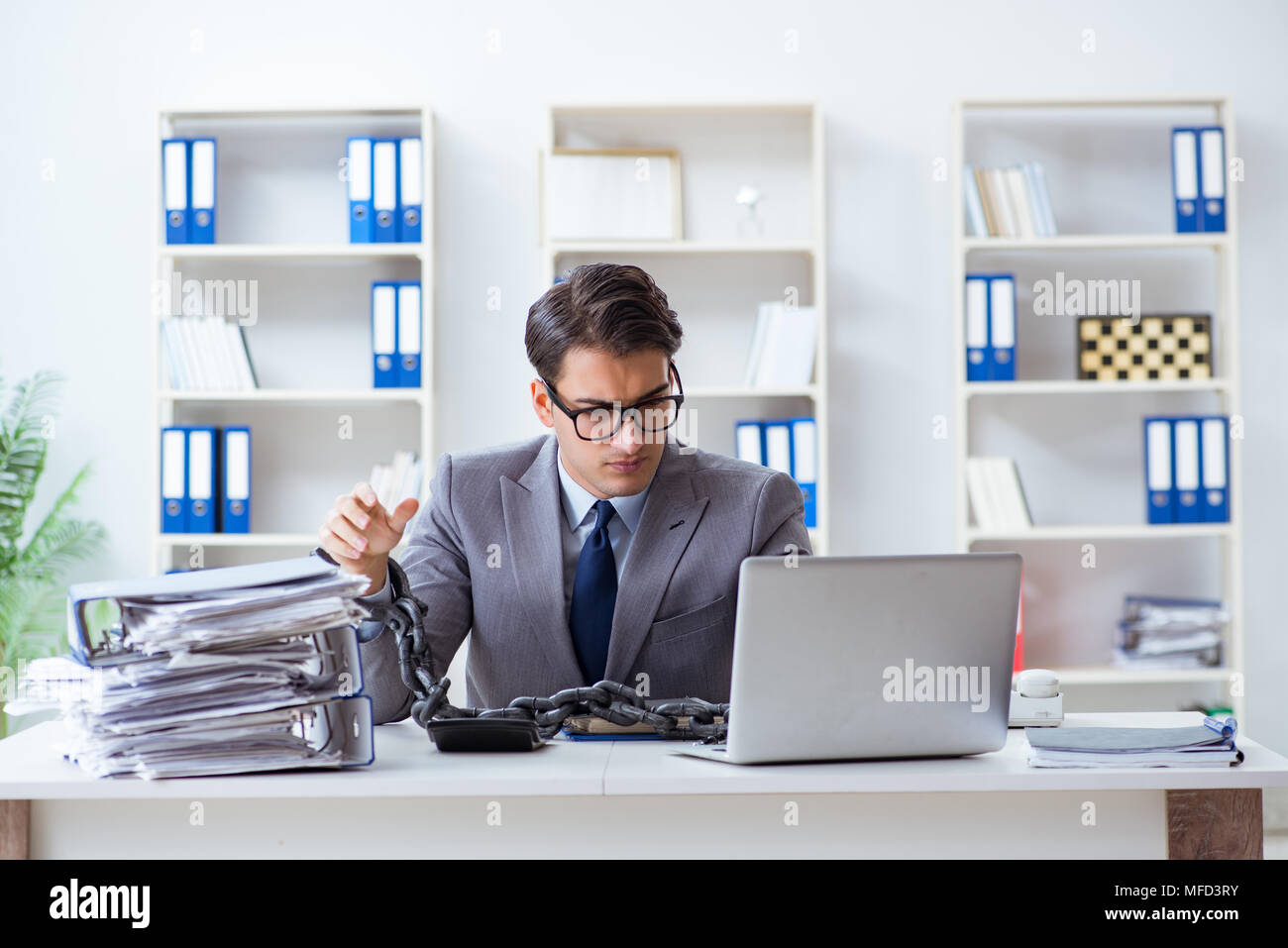 Busy employee chained to his office desk Stock Photo - Alamy