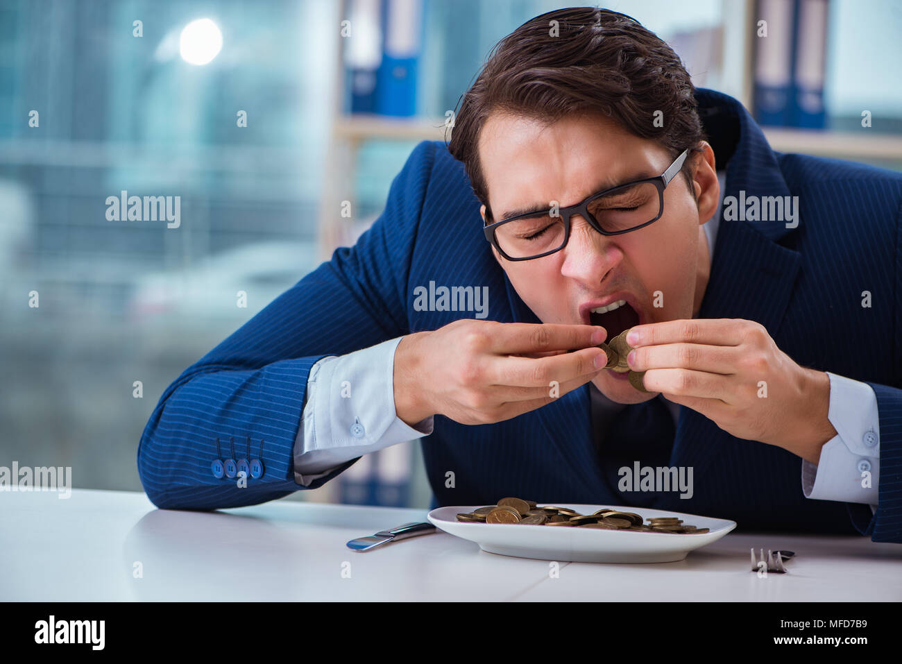 Funny businessman eating gold coins in office Stock Photo - Alamy