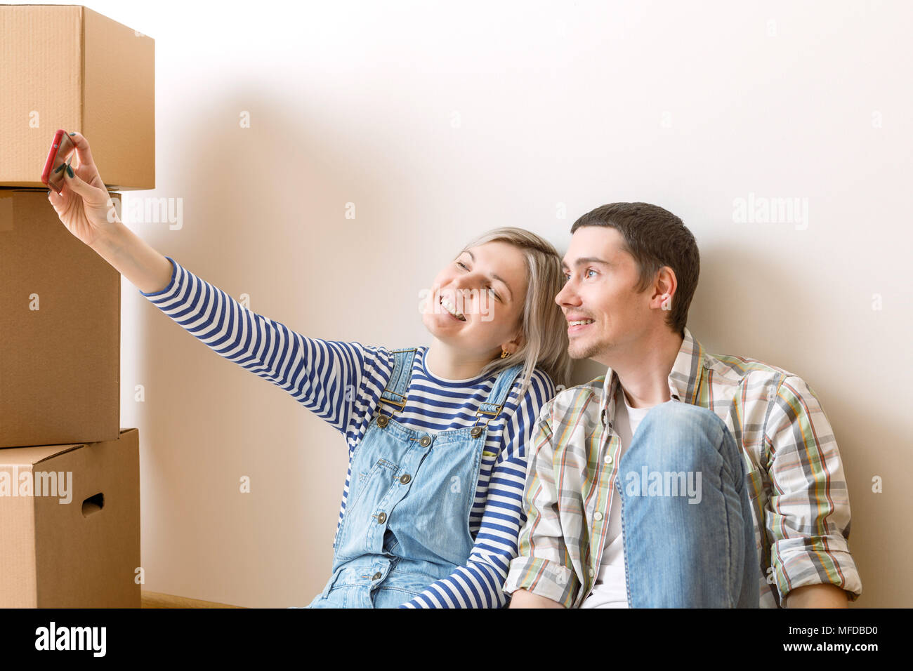 Photo of young married couple doing selfie sitting on floor among ...