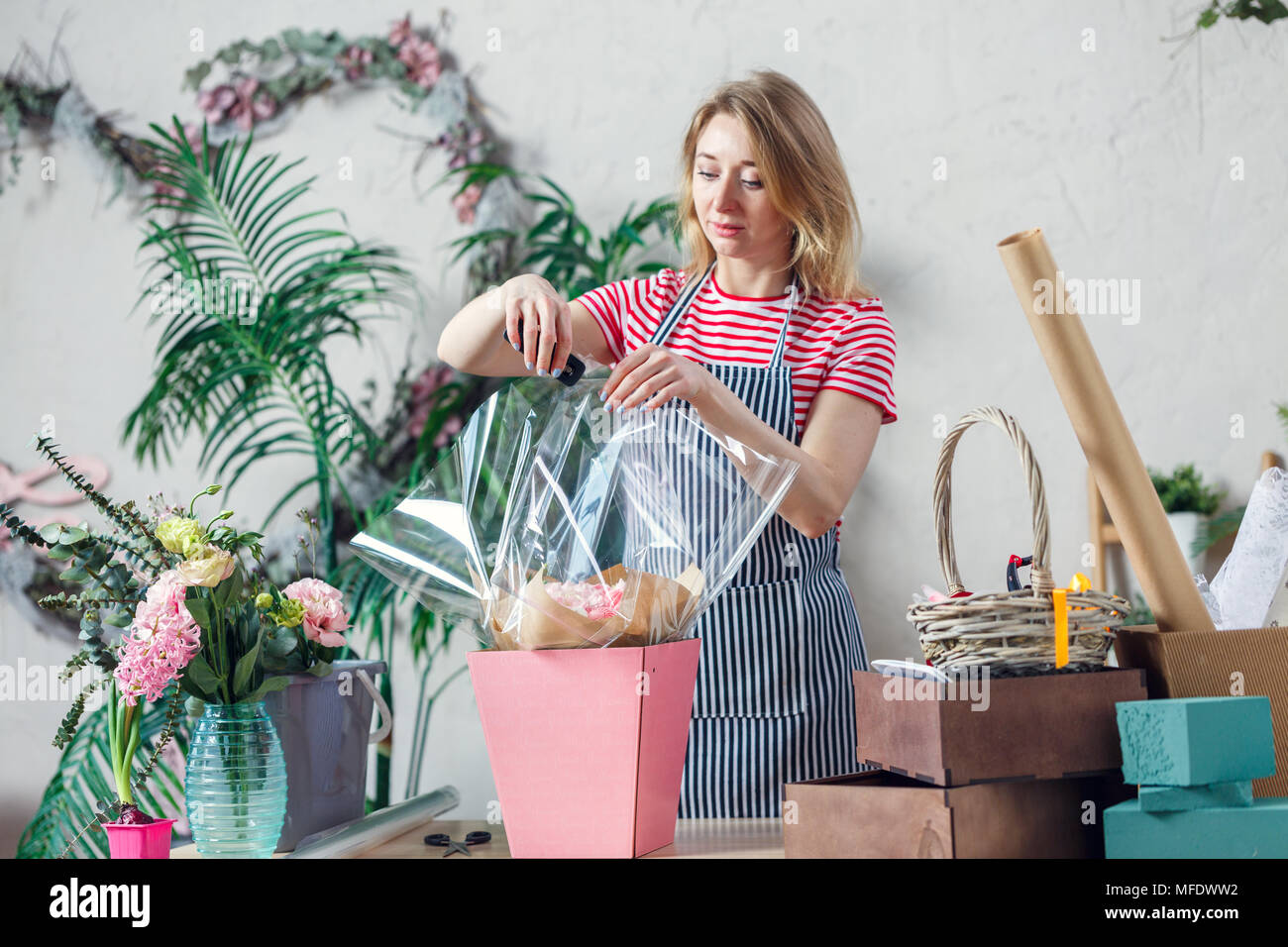 Picture of florist woman with stapler decorating flower arrangement at ...