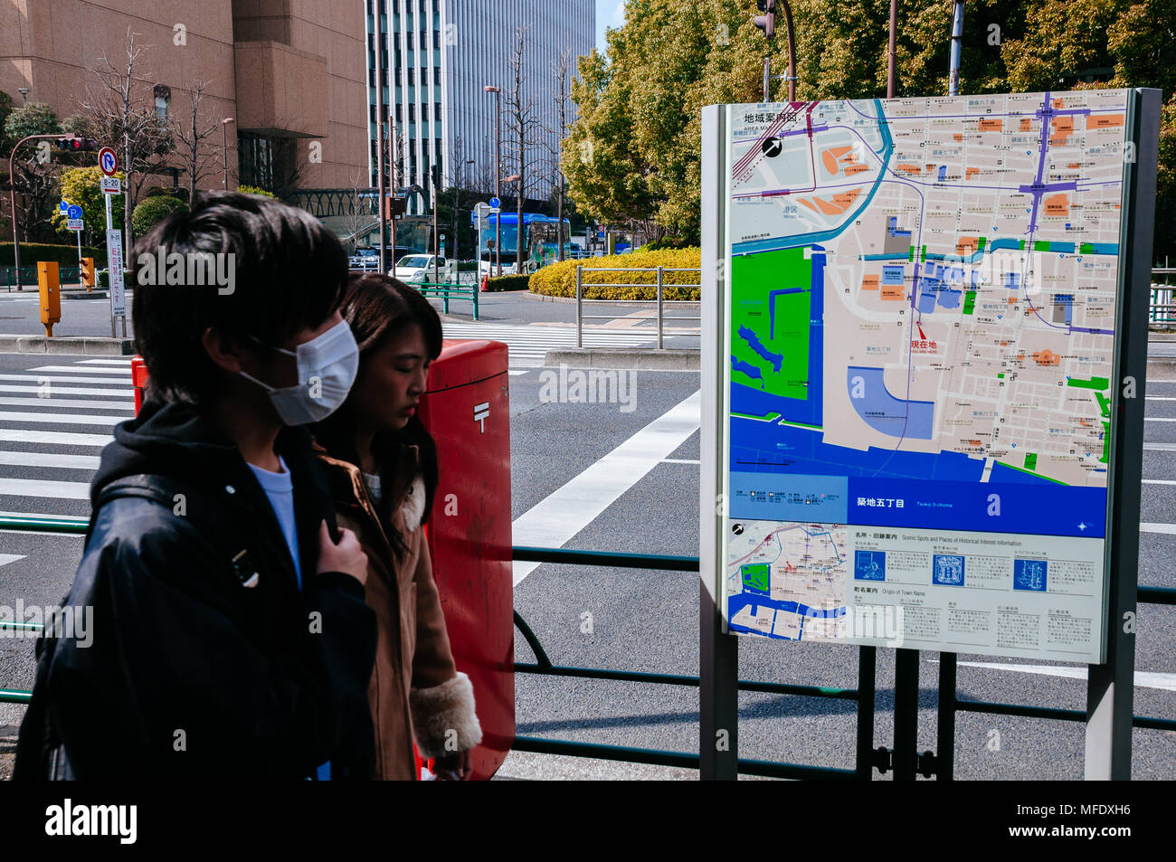 Young couple walking down street passing by information board with city ...