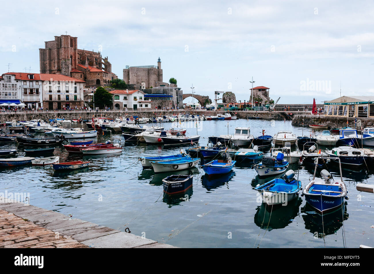 Boats moored at the port with Santa María de la Asunción church, the ...