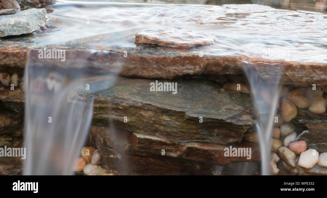 Water flowing on two side of a small cascade of rocks Stock Photo - Alamy