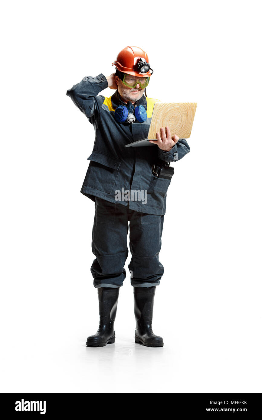 The studio shot of pensive senior bearded male miner standing at the ...