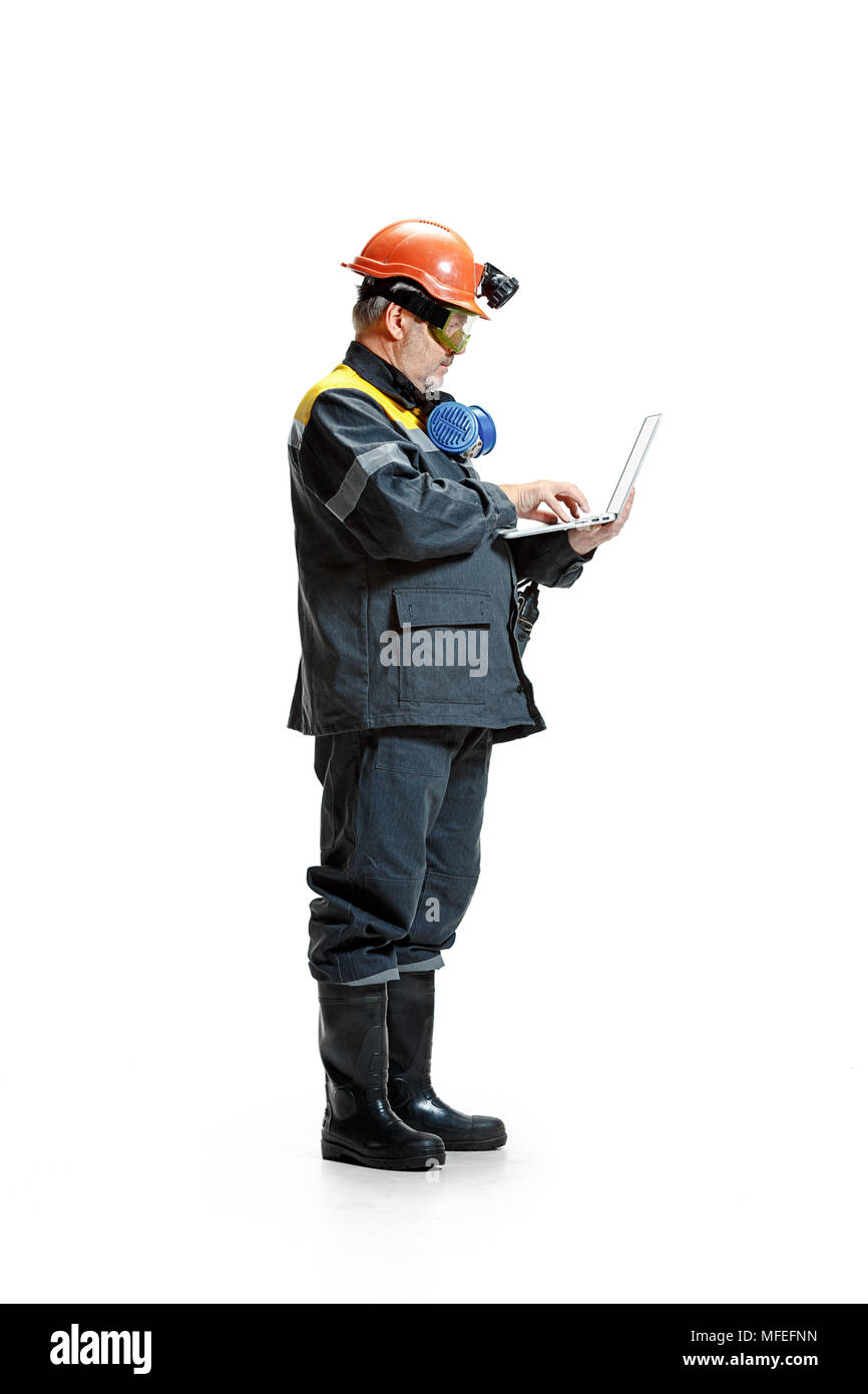 The studio shot of serious senior bearded male miner standing in ...
