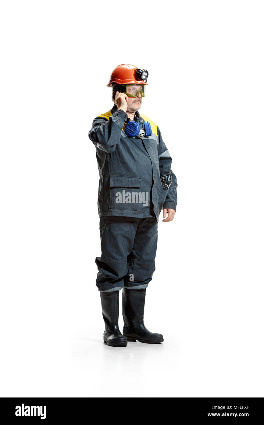 The studio shot of serious senior bearded male miner standing in ...
