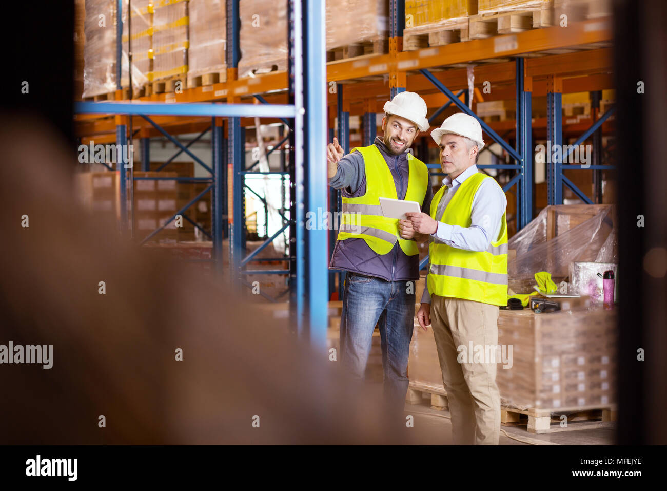 Nice positive man pointing at the storage shelves Stock Photo - Alamy
