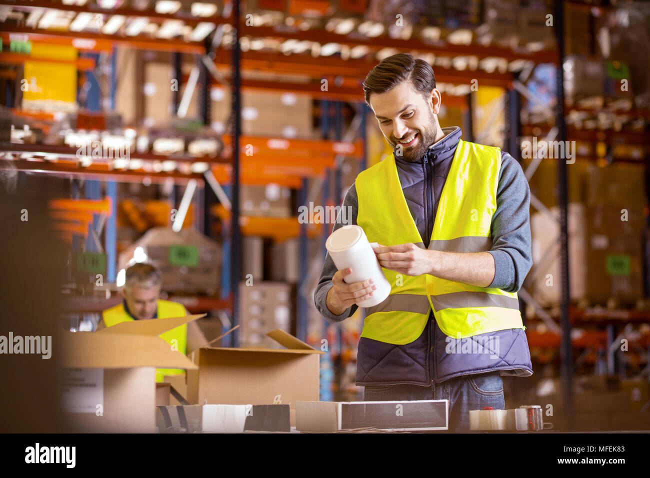 Joyful warehouse worker putting stickers Stock Photo - Alamy