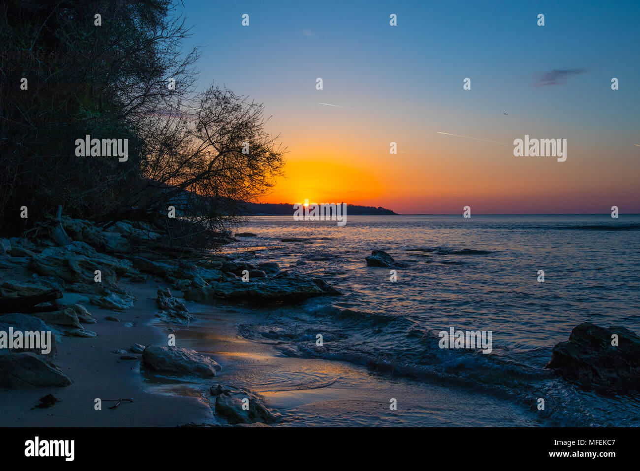 Sunrise on the beach with rocks and trees Stock Photo - Alamy
