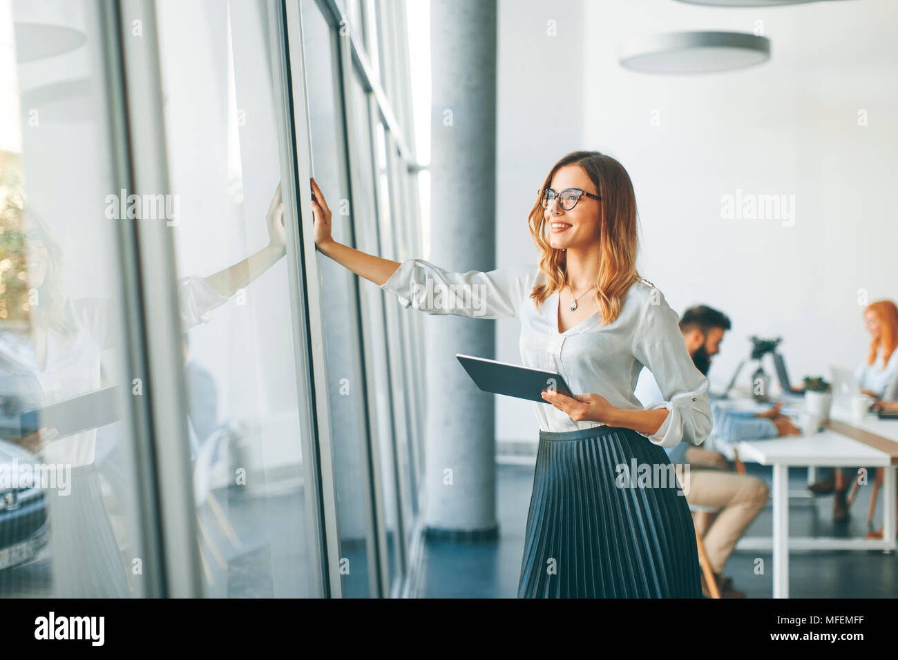 Young attractive female manager working on digital tablet while ...
