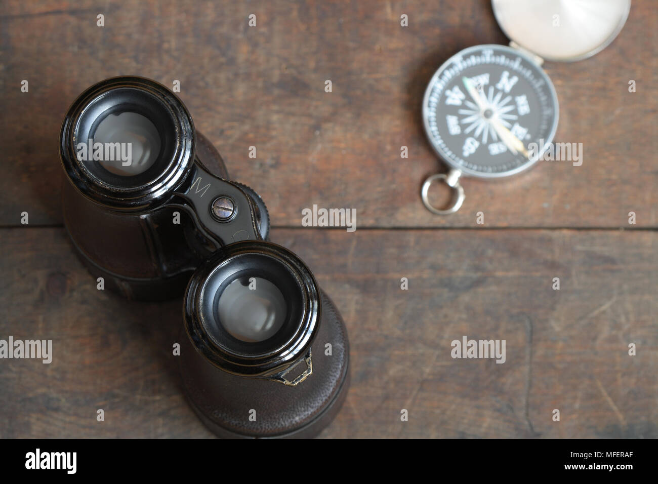 Still life with antique binoculars and compass on wooden background ...