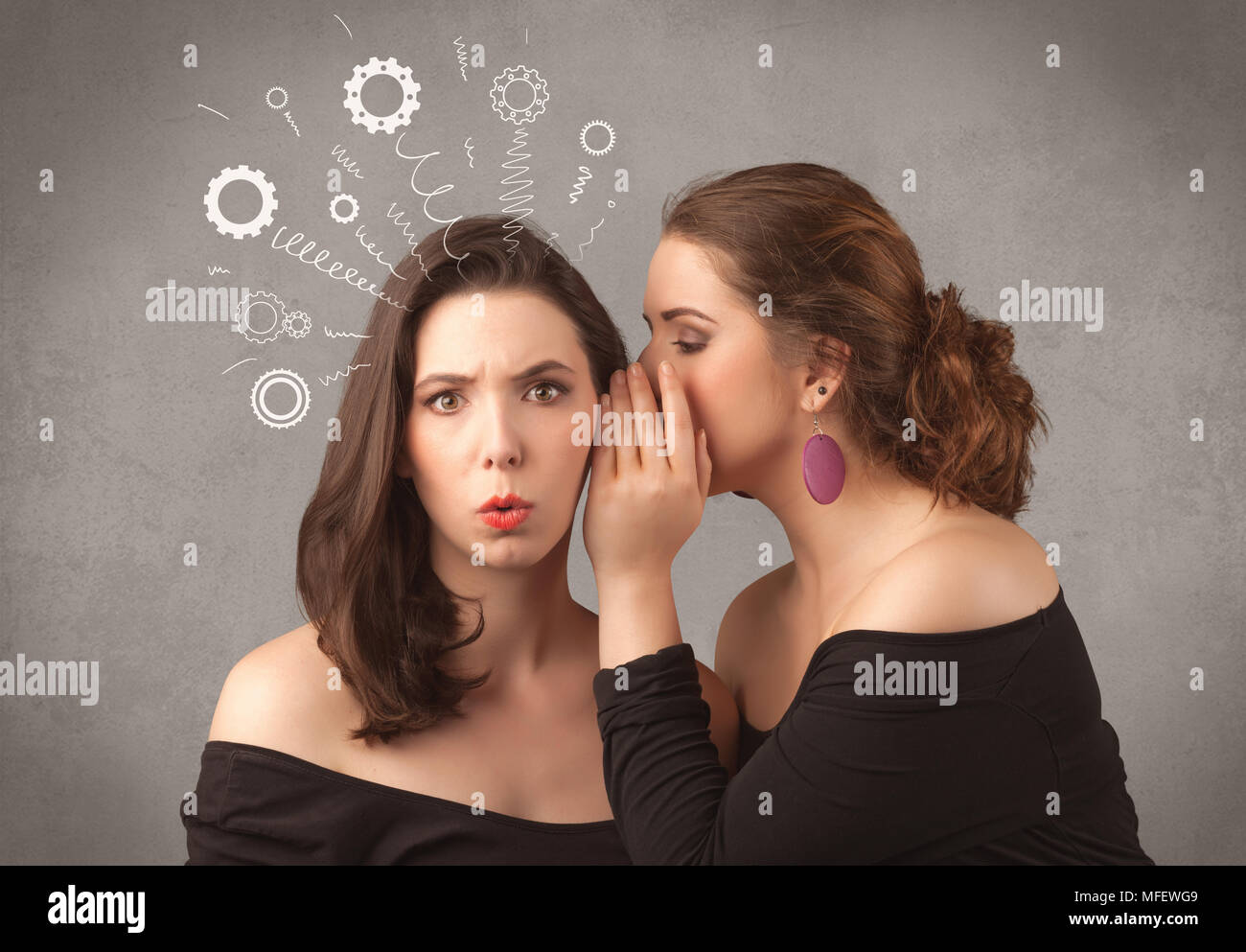 Two girlfriends in elegant black dress sharing secrets with each other ...
