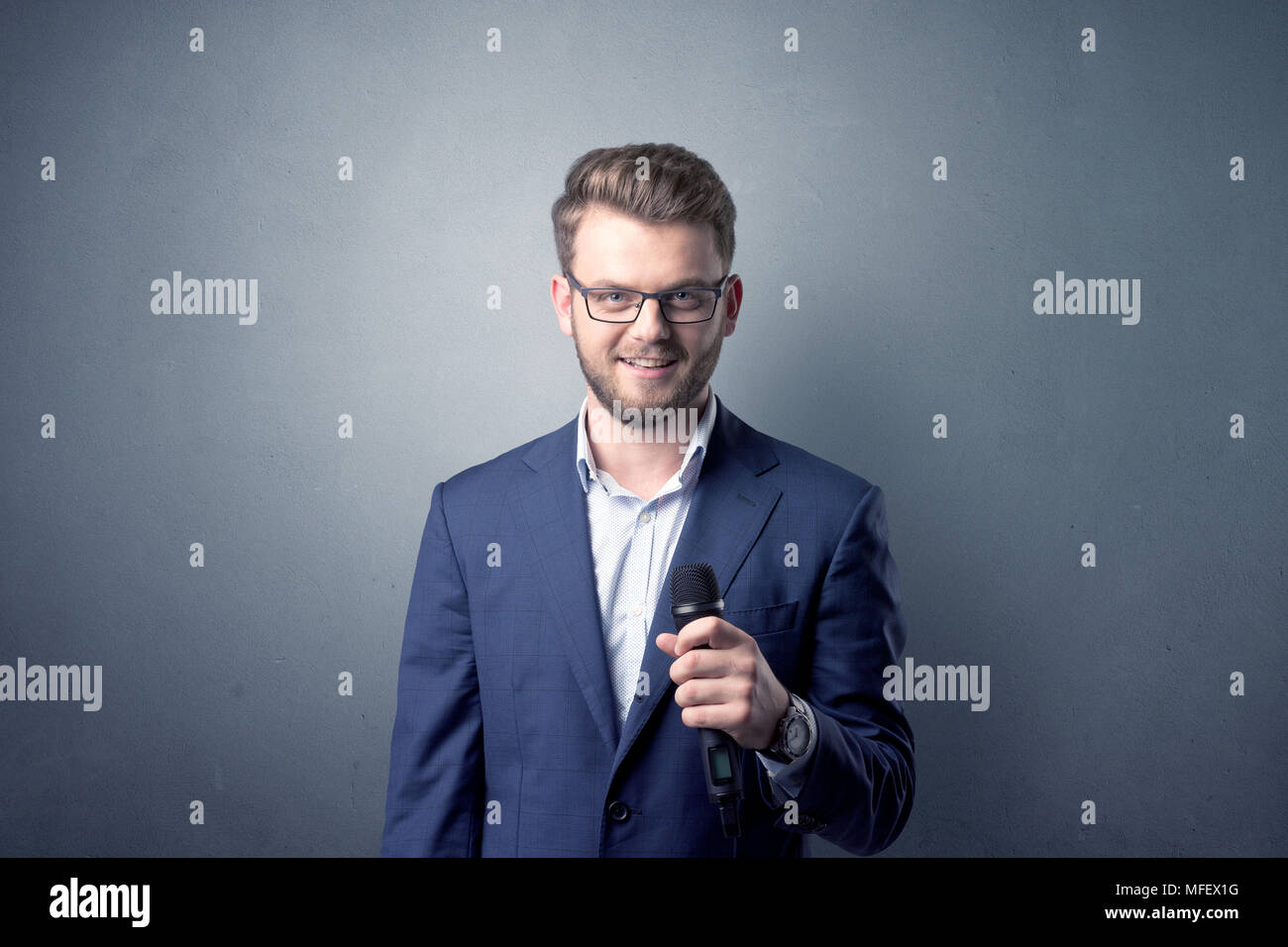 Businessman speaking into microphone with blue background Stock Photo ...